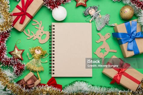 깨끗한 페이지와 크리스마스 트리 장식 새해 장난감과 선물 상자 녹색 배경 노트북 메리 크리스마스와 새해를위한 준비 및 계획의 개념 플랫 레이 상단 보기 12월에 대한 스톡