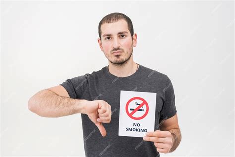 Free Photo A Young Man Holding No Smoking Sign Showing Thumbs Down