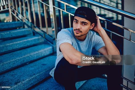 잘생긴 젊은 남자의 초상화 카메라 보고 계단에 앉아 캐주얼 거리 복장을 입고 유행 멋진 의류 및 브랜드 이름 또는 레이블 복사 공간 야구 Hipster 남자 수염 갈색에