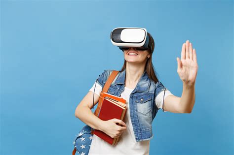 가상 현실 헤드셋에서 젊은 여자 학생 부동 파란색 배경에 고립 된 가상 화면에서 가리키는 푸시 버튼 같은 것도 터치 개최 학교 대학 대학에서 교육입니다 20 29세에 대한