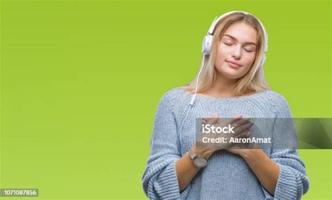 젊은 백인 여자와 웃 고 고립 된 배경 위에 음악 착용 헤드폰을 듣고 닫힌된 눈과 얼굴에 감사 제스처와 함께 가슴에 손 건강 개념입니다 헤드폰에 대한 스톡 사진 및 기타