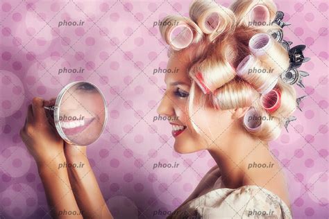 عکس خانم با مو های طلایی در حال فر کردن مو با بیگودی و نگاه کردن در