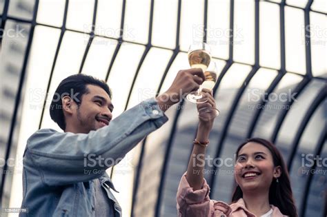옥상에서 함께 기념일 파티를 축하하는 아시아 젊은 부부 화이트 와인 토스트 한 잔을 들고 행복과 미소로 마시는 남자와 여자 어린 소년과 소녀 개념의 사랑 20 24세에 대한