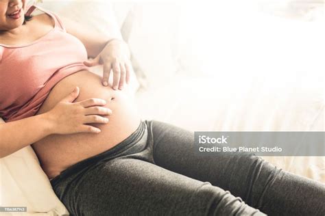 임신 한 여자는 그녀의 아이를 돌보는 동안 집에서 행복을 느낀다 임신 한 배에 아기를 들고 젊은 기대 어머니 출산 전 관리 및 여성 임신 개념 가족에 대한 스톡 사진 및