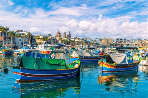 Landscape With Traditional Luzzu Boat In Harbor Of Marsaxlokk Malta