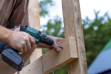 Hands Of Man Using Drill To Assemble Wooden Structure Precision And Skill Required In DIY