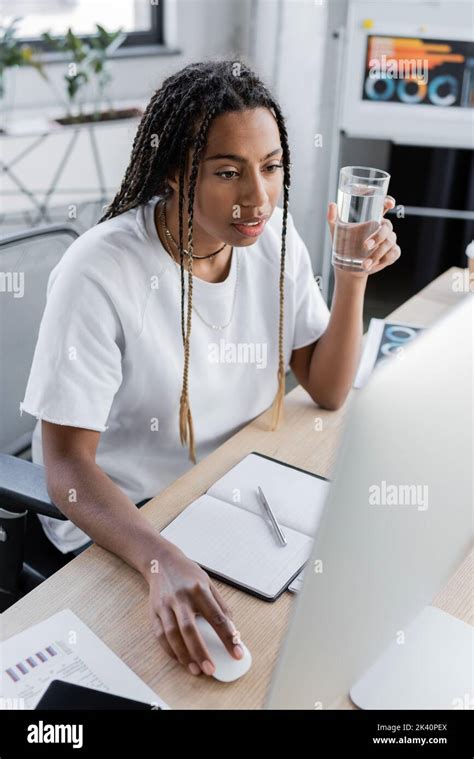 African American Businesswoman Holding Glass Of Water And Using