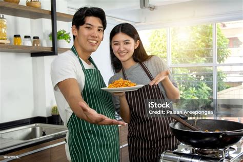 쾌활 한 행동에 앞치마에서 귀여운 행복 한 부부의 초상화 현대 부엌에서 음식의 성분으로 장식 마 카로 니 테이블의 아침 식사를