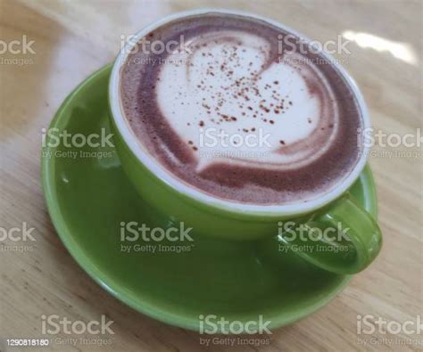 로프트 스타일의 커피 숍의 나무 책상 테이블에 녹색 머그잔에 장식 콩 코코넛 젖소 우유의 심장 모양의 말차 핫 초콜릿 라떼 0