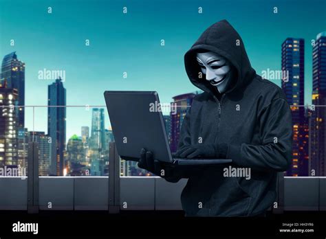 Hooded Hacker With Vendetta Mask Stealing Information With Laptop In