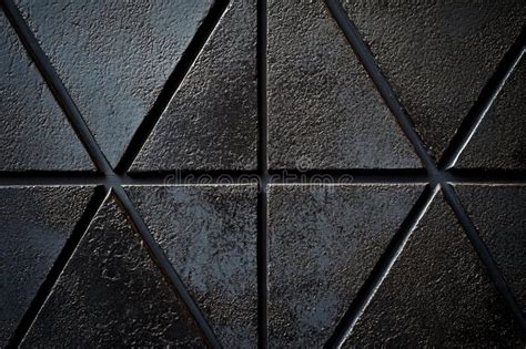 Textured Black Triangular Tiles Arranged In A Geometric Pattern On A