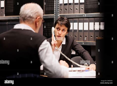 Woman Investigator Talking At Landline Phone With Remote Inspector Discussing Missing Person