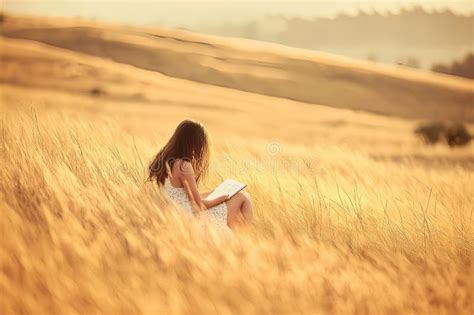 a peaceful scene of a woman sitting in a field of tall golden grass