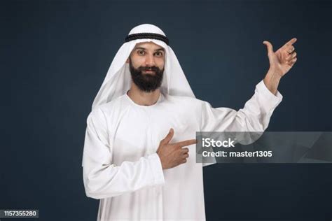 어두운 파란색 스튜디오 배경에 아라비아 어 사우디 사람 가리키기에 대한 스톡 사진 및 기타 이미지 가리키기 아랍에미리트 연합 남자 Istock