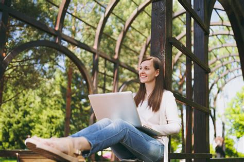 가벼운 캐주얼 옷에 젊은 성공적인 사업가 봄 자연에 야외 거리에 도시 공원에서 현대 노트북 Pc 컴퓨터에서 작업 하는 여자를 웃 고 모바일 사무실입니다 프리랜서 비즈니스
