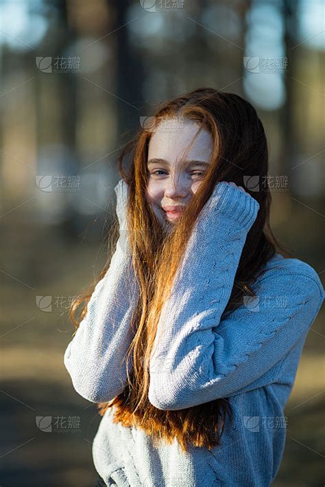 红发小女孩在公园里摆姿势拍照。