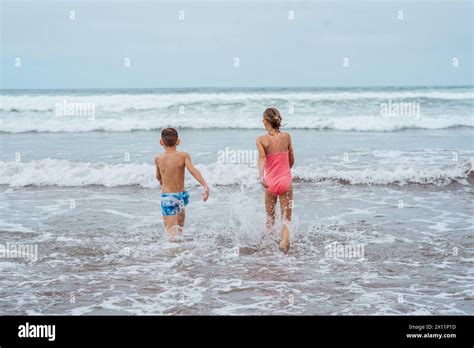 Siblings Playing On Beach Running Skipping Having Fun On Sandy Beach