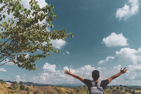 배낭 여행자 남자는 푸른 하늘과 흰색 구름 추상적 인 배경산 꼭대기에 손을 올립니다 복사 공간 자유 여행 모험과 좋은 개념을