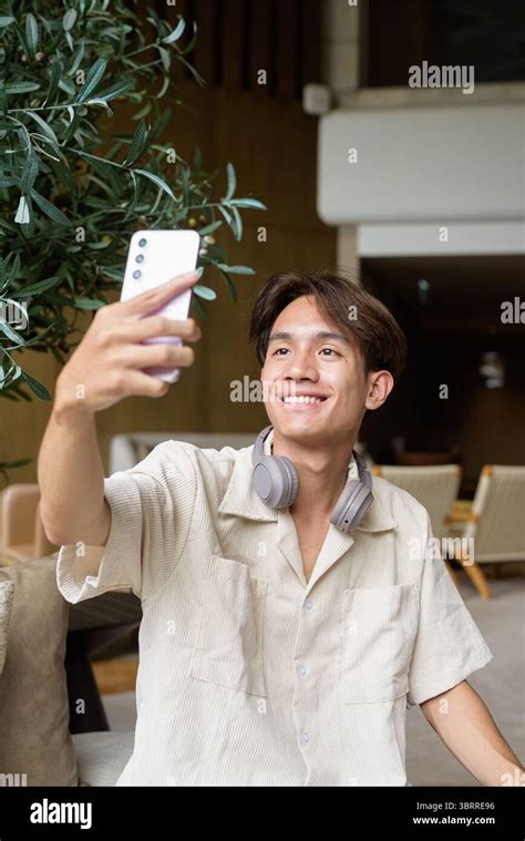 Non Binary Cute Asian Student Man Sitting In Modern Coffee Shop Stock