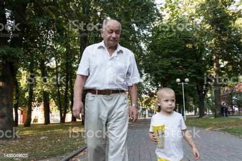 할아버지와 손자는 팝콘 한 잔과 함께 길을 따라 공원을 걷고 있습니다 노인과 어린 소년은 이동 중에도 간식을 먹습니다 그리스 문화에 대한 스톡 사진 및 기타 이미지 Istock