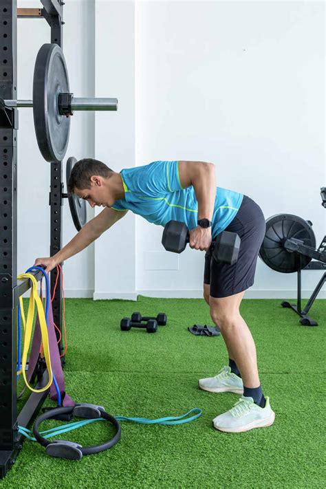 A Young Man Is Shown Selecting Resistance Bands While Holding Dumbbells
