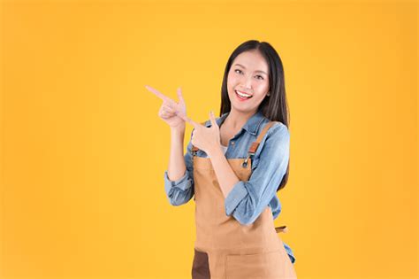 예쁜 아시아 여성 스마일 커피 프리랜서 자신의 커피 바 숍은 커피 종이 컵을 들고 자신의 상점 노란색 배경에서 신용 카드를 스 와이프하는 단말기 돈을 통해 신용 카드로