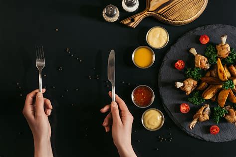 블랙에 포크와 나이프와 소스와 구운된 치킨 맛 있는 구운된 감자를 들고 사람의 부분 평면도 검정색 배경에 대한 스톡 사진 및 기타 이미지 검정색 배경 손 먹기