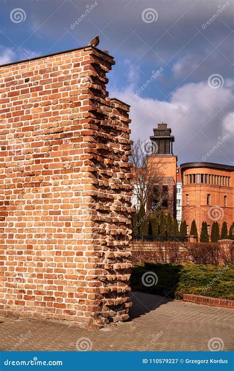 Fragment Of A Medieval Defensive Wall And Red Brick Buildings Stock