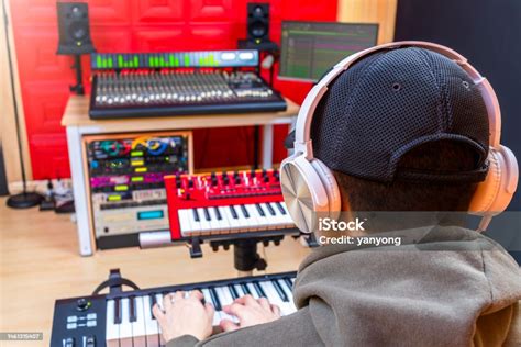 아시아 남성 음악 프로듀서 작곡가의 뒷면은 홈 스튜디오에서 Midi 키보드로 노래를 녹음합니다 음악 제작 컨셉 놀기에 대한 스톡