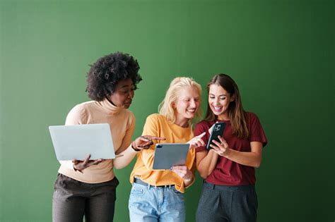 녹색 배경에서 웃으며 스마트 기기를 사용하는 세 명의 다문화 친구들 20 24세에 대한 스톡 사진 및 기타 이미지 20 24세 25 29세 30 34세 Istock