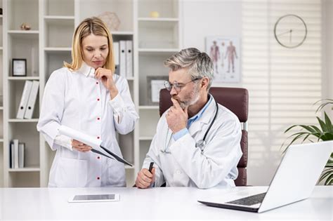 회의에 참석한 진지한 의사 흰 의료복을 입은 남녀 진료소 직원 환자 진단에 대해 이야기하고 토론하는 진료소 진료실 진료실 내부 근무 가상현실에 대한 스톡 사진 및 기타