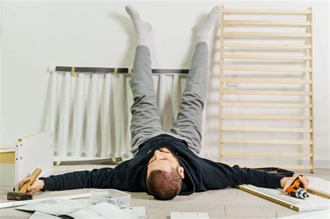 집에서 바닥에 누워 있는 한 남자가 Diy 가구를 파괴하고 필사적으로 피곤하게 만들려고 셀프 조립 프로젝트 중에 지쳤습니다 35