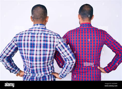 Young Gay Couple Of Two Men Wearing Casual Clothes Standing Backwards Looking Away With Arms On