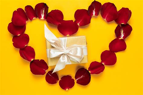 노란 배경에 큰 마음의 형태로 장미 꽃잎으로 만든 사랑의 상징 상자는 새틴 활공예 용지에 포장되어 있습니다 2월에 대한 스톡
