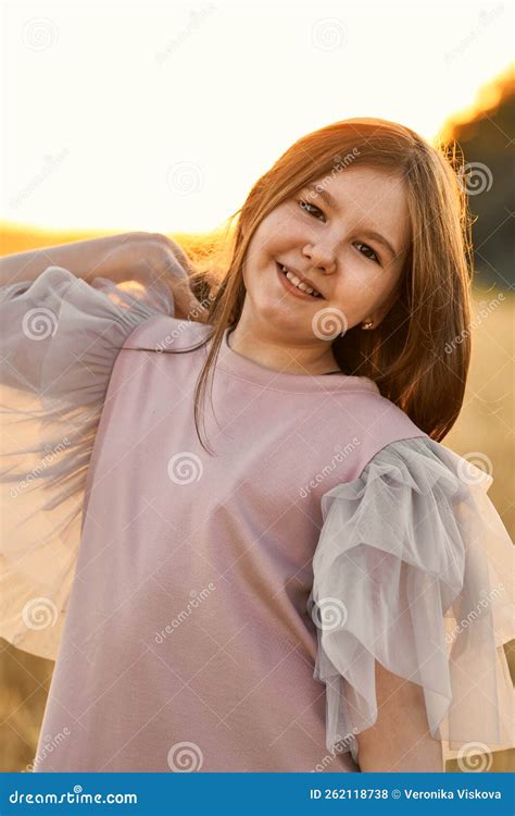 Portrait Of Pretty Smiling Girl With Long Hair In The Field In Sunset