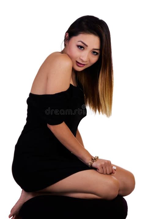 Attractive Asian American Woman Kneeling In Black Dress On White Stock