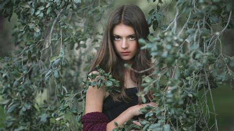 Blonde Girl Model Is Standing In Tree Branches Background Wearing Black