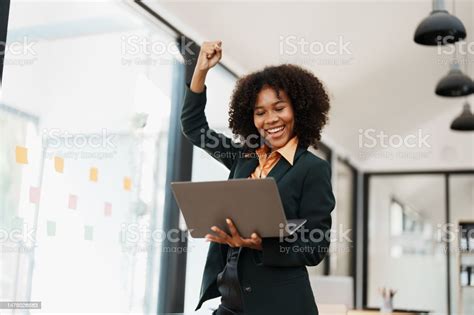 아름다운 젊은 십대 미국 아프리카 비즈니스 여성은 우승자에 손을 들고 컴퓨터 노트북을 들고 제스처입니다 성취 성공을 축하하는 성공을 기쁘게 생각합니다 기업가에 대한 스톡