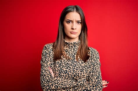 빨간 배경 회의적이고 긴장 교차 된 팔로 얼굴에 표정을 거부 위에 서 캐주얼 스웨터를 입고 젊은 아름다운 갈색 머리 여자 부정적인 사람 겨울에 대한 스톡 사진 및 기타