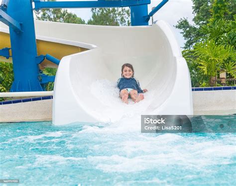 워터파크나 리조트 호텔의 소녀가 워터 슬라이드를 타고 수영장으로 미끄러져 내려간다 워터 슬라이드에 대한 스톡 사진 및 기타 이미지 워터 슬라이드 워터 파크 4 5세