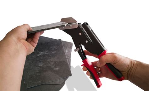 남자의 손은 새로운 전문 도구 커터 빨간색 손잡이가있는 검은 색 흰색 배경에 고립 된 검은 색 외부 집 벽 굴뚝 및 왼쪽의 지붕을위한 천연 슬레이트 시트로 슬레이트를 잘라