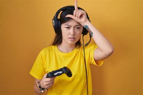 Chinese Young Woman Playing Video Game Holding Controller Making Fun Of People With Fingers On