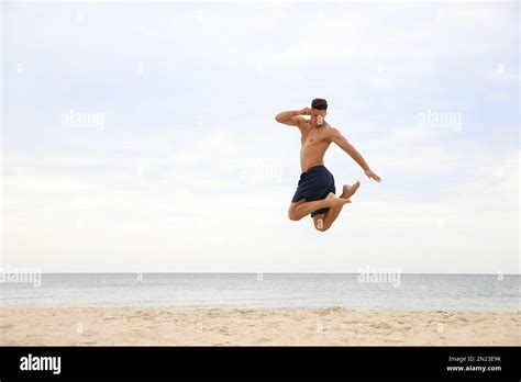Muscular Man Jumping On Beach Space For Text Body Training Stock Photo Alamy