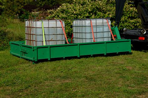 금속 케이지에 두 개의 플라스틱 용기 더운 날씨에 가축에게 물을 주거나 마시기위한 물이 가득합니다 자동차는 컨테이너를 뒷바퀴로