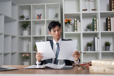 Young Professional In Suit Reviewing Documents At Desk Analyzing