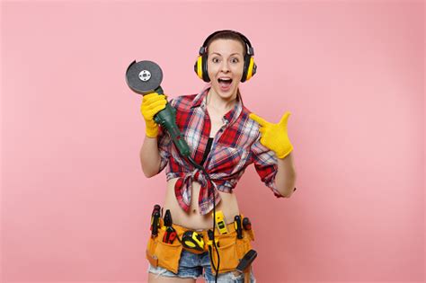 노란 장갑에 강한 젊은 핸디 여자 소음 절연 헤드폰 키트 도구 벨트 유력 본 분홍색 배경에 고립의 전체 여성 남성 작업입니다 혁신 개념입니다 Diy에 대한 스톡 사진 및