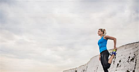 이어폰을 낀 젊은 스포티한 여성 러너가 자연 속 해변에서 뻗어 있다 공간을 복사합니다 사진 Unsplash의 복사 공간 이미지