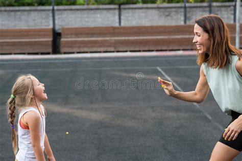 Mom And Daughter Have Fun On The Outdoor Sports Ground A Caucasian Woman Throws Candy And A