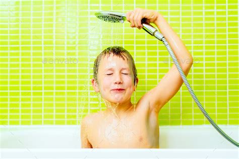 Boy In The Bathtub Washes His Head With Water Sprayed From The Shower