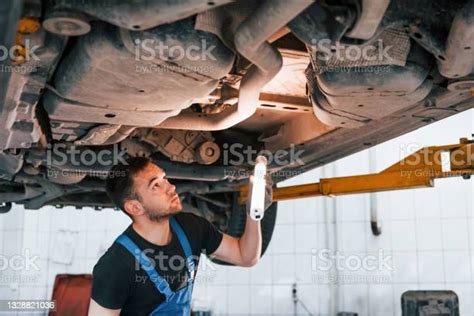 조명 장비를 사용합니다 작업 복을 입은 남자는 실내에서 흰색 자동차를 수리합니다 자동차 서비스의 개념 20 24세에 대한 스톡